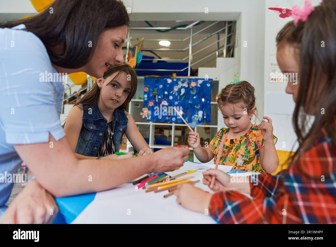 Creative kids during an art class in a daycare center or elementary school classroom drawing ...
