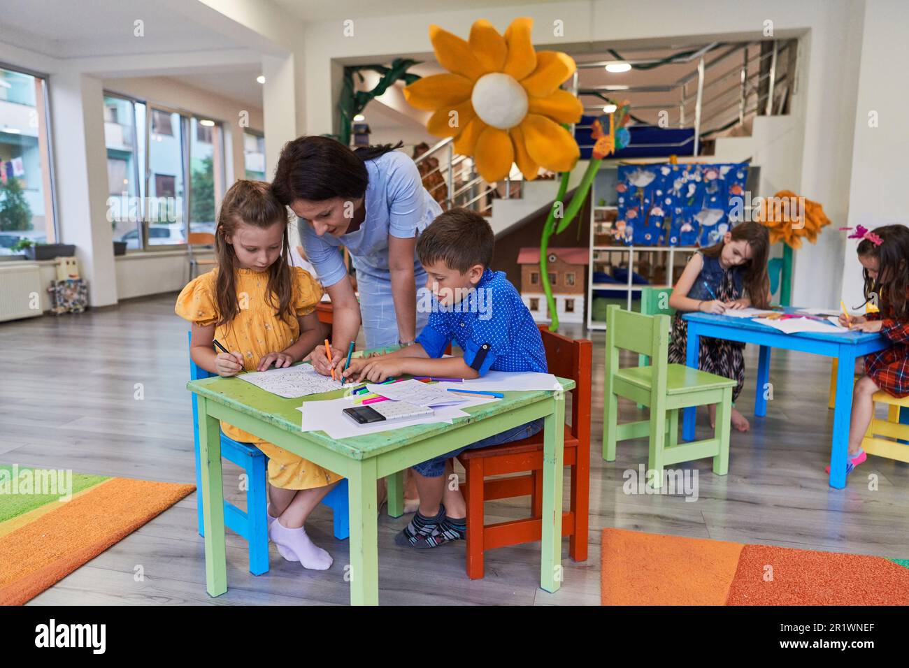 Creative kids during an art class in a daycare center or elementary school classroom drawing ...