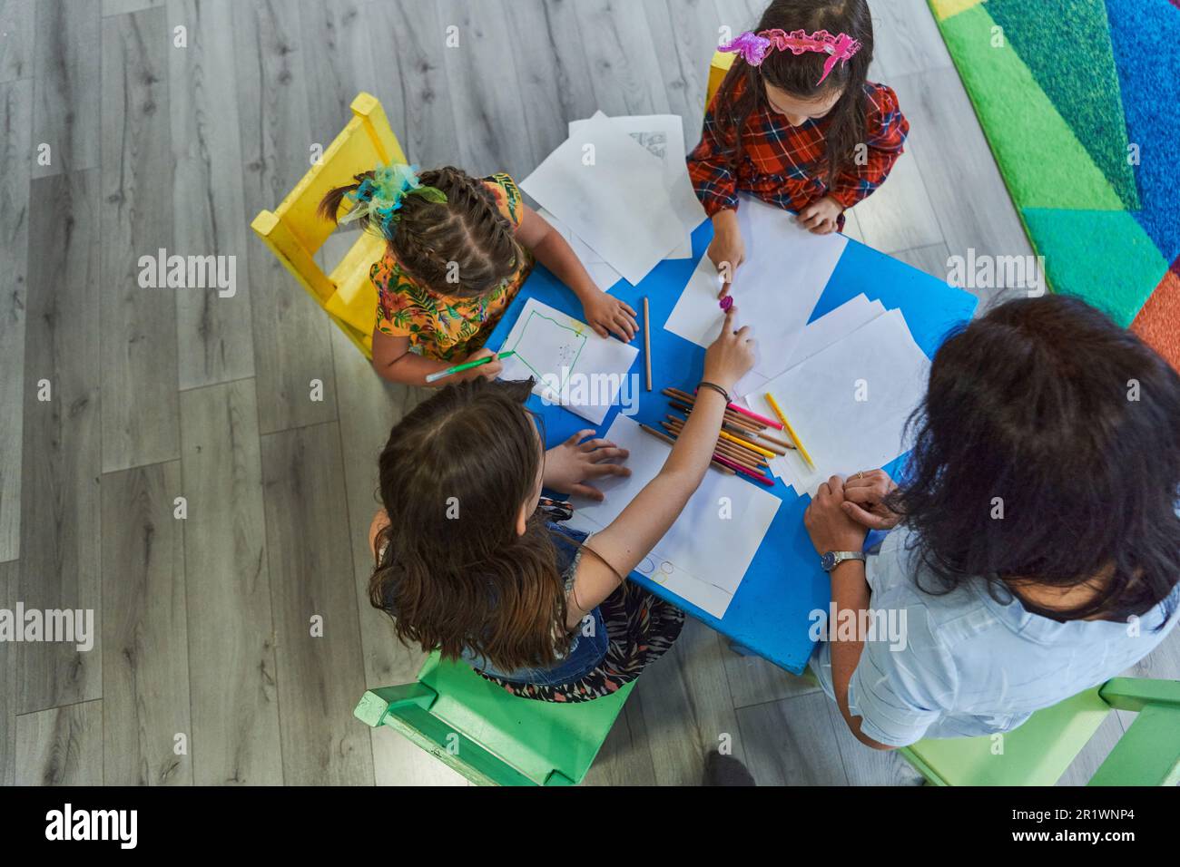 Creative kids during an art class in a daycare center or elementary school classroom drawing ...