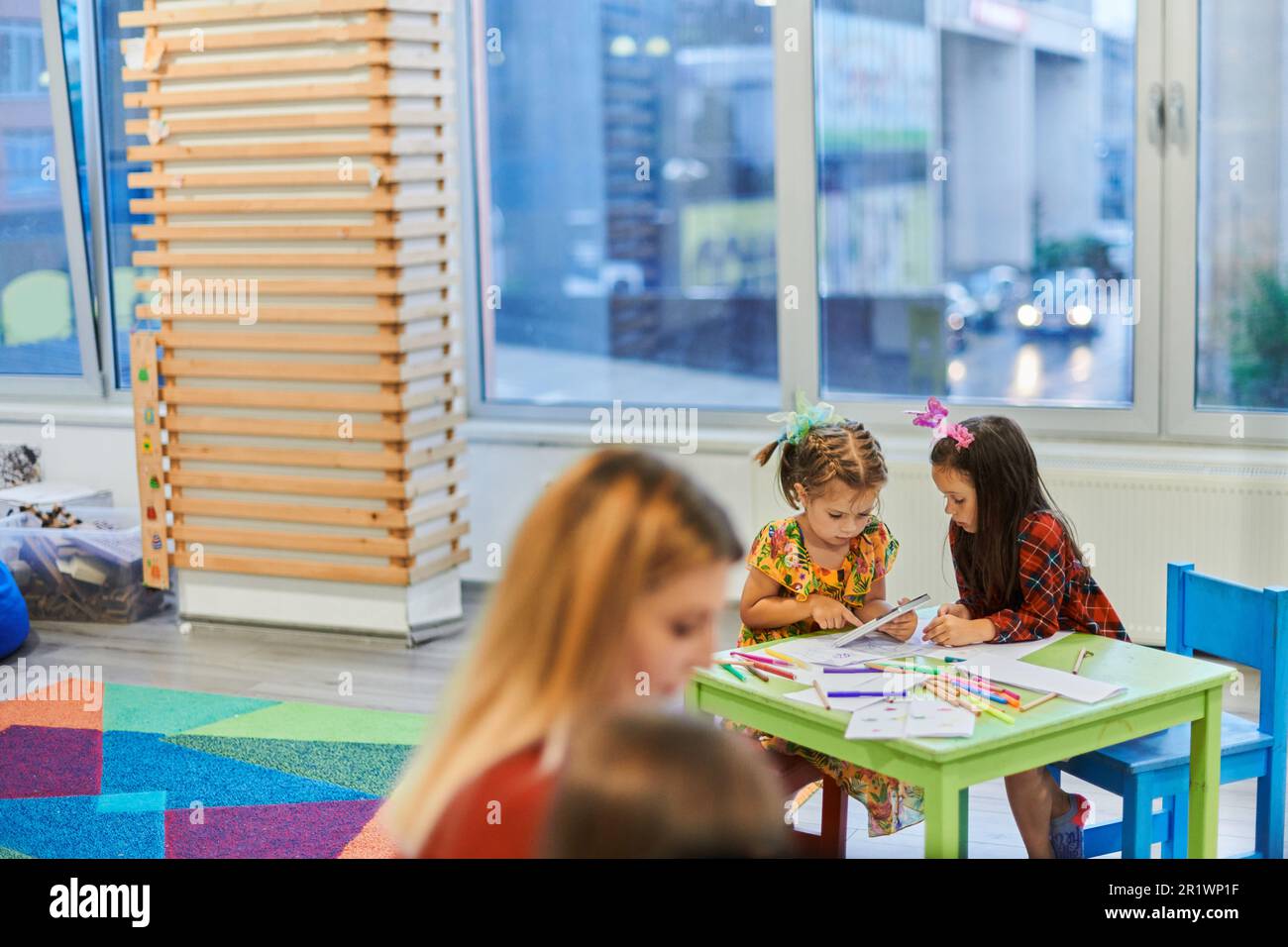 Creative kids during an art class in a daycare center or elementary school classroom drawing ...