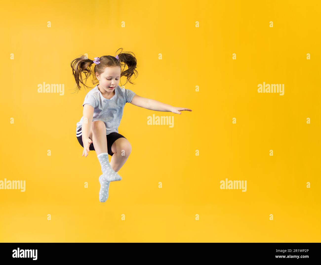 Happy little girl jumping on yellow background Stock Photo - Alamy