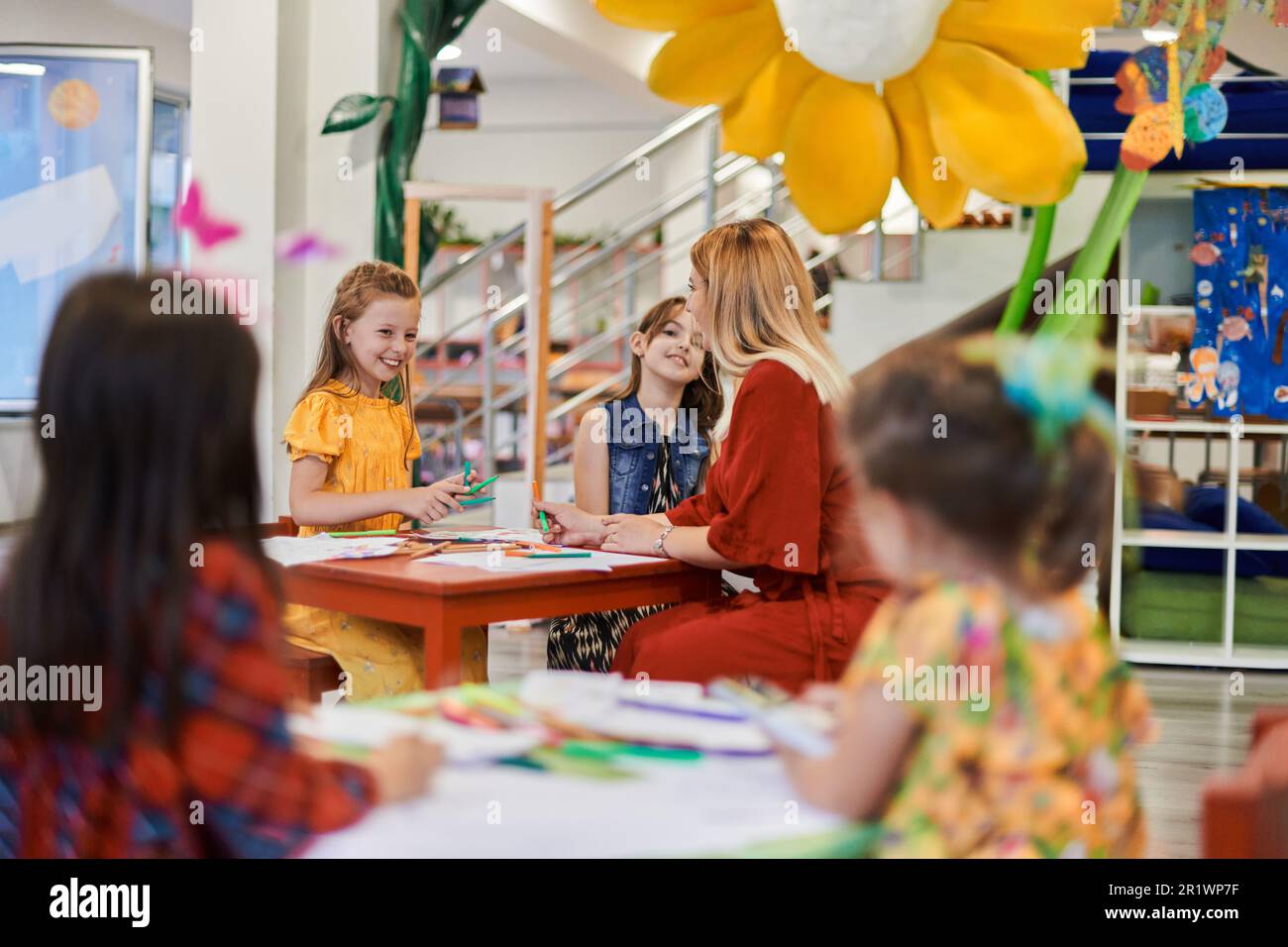 Creative kids during an art class in a daycare center or elementary school classroom drawing ...