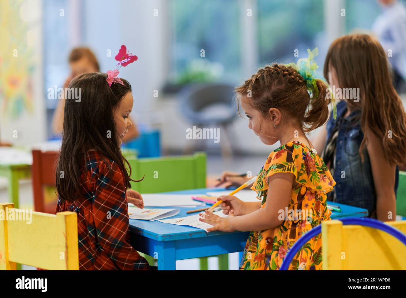 Creative kids during an art class in a daycare center or elementary school classroom drawing ...