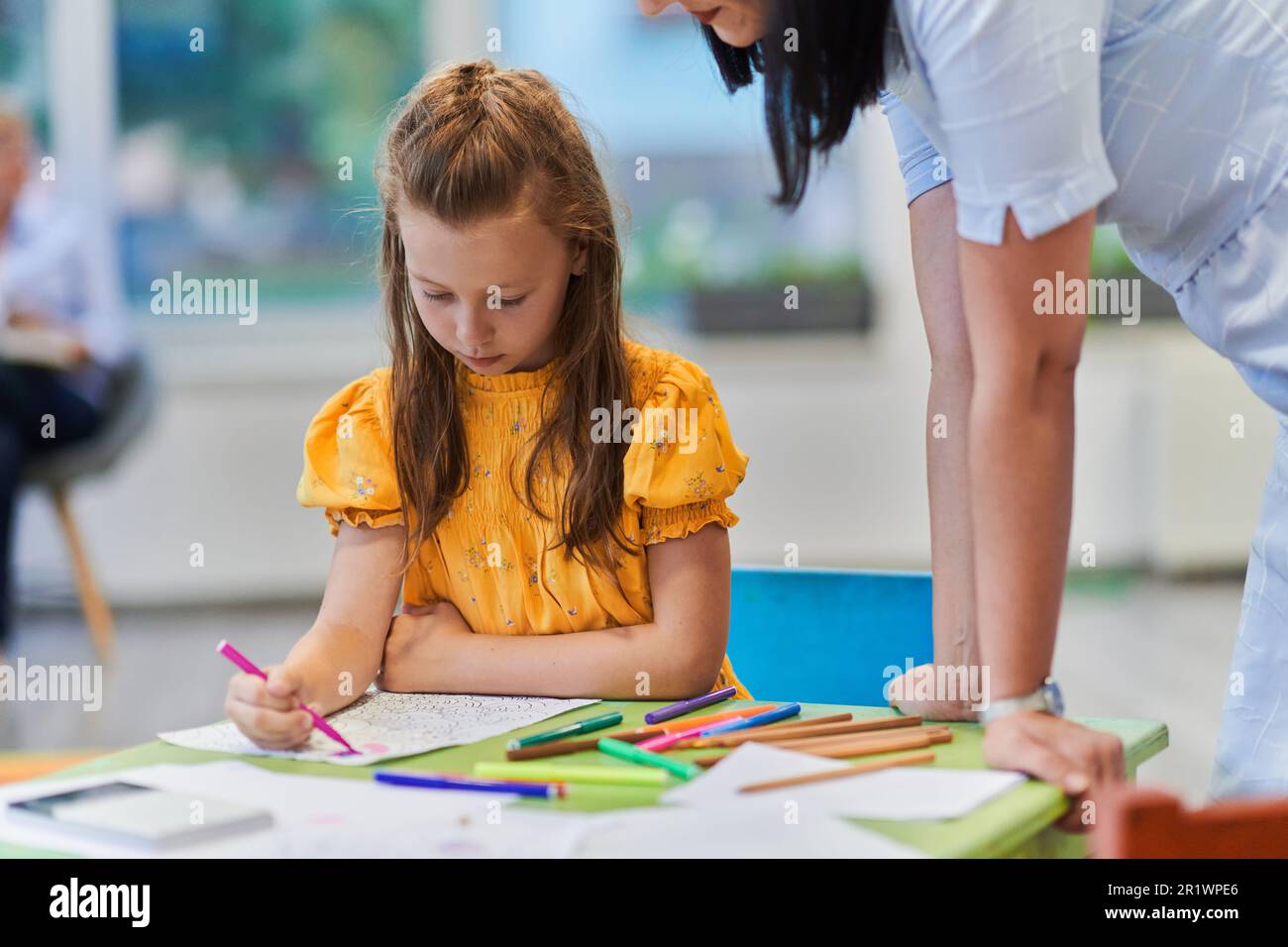 Creative kids during an art class in a daycare center or elementary school classroom drawing ...