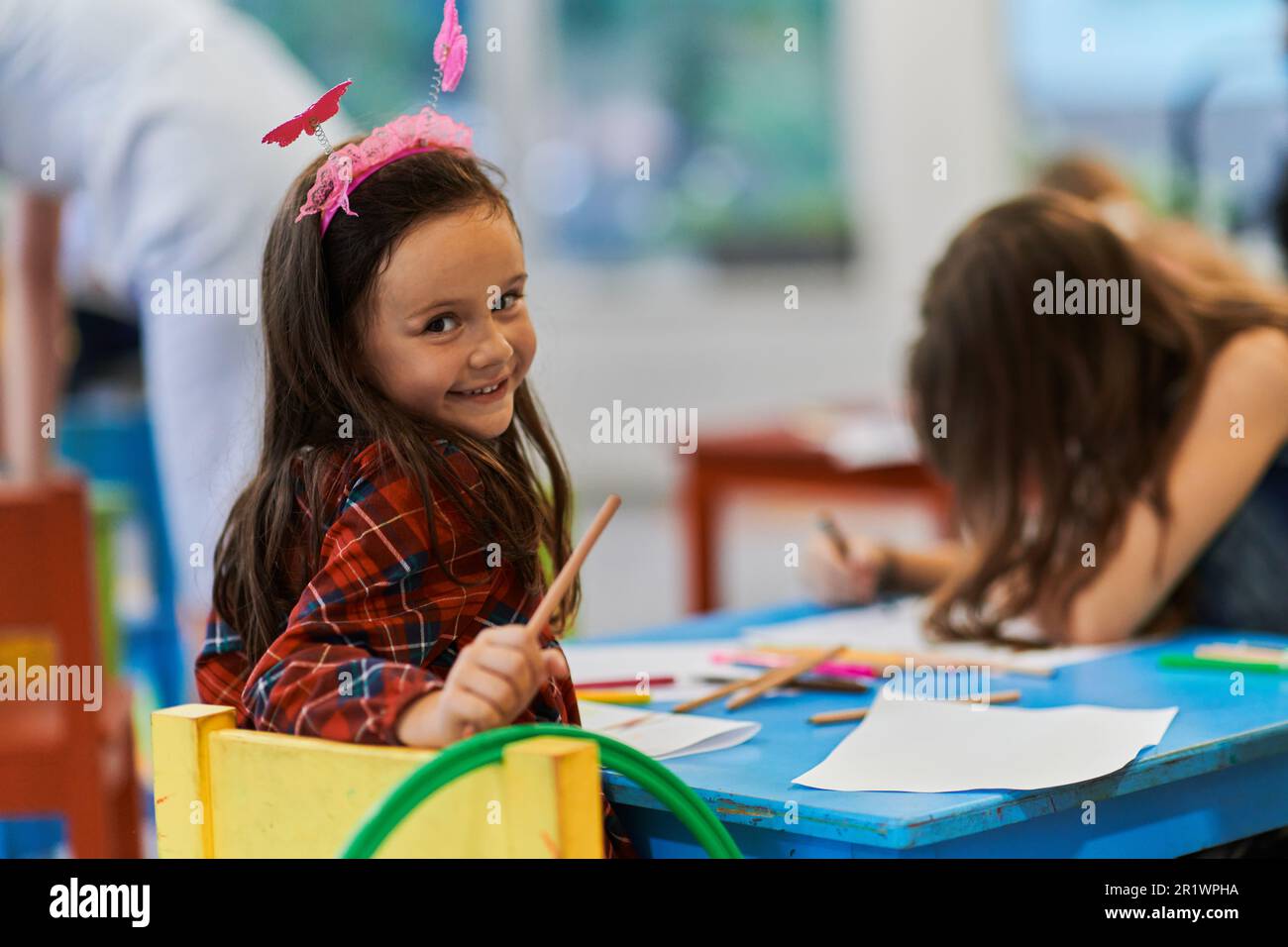 Creative kids during an art class in a daycare center or elementary school classroom drawing ...