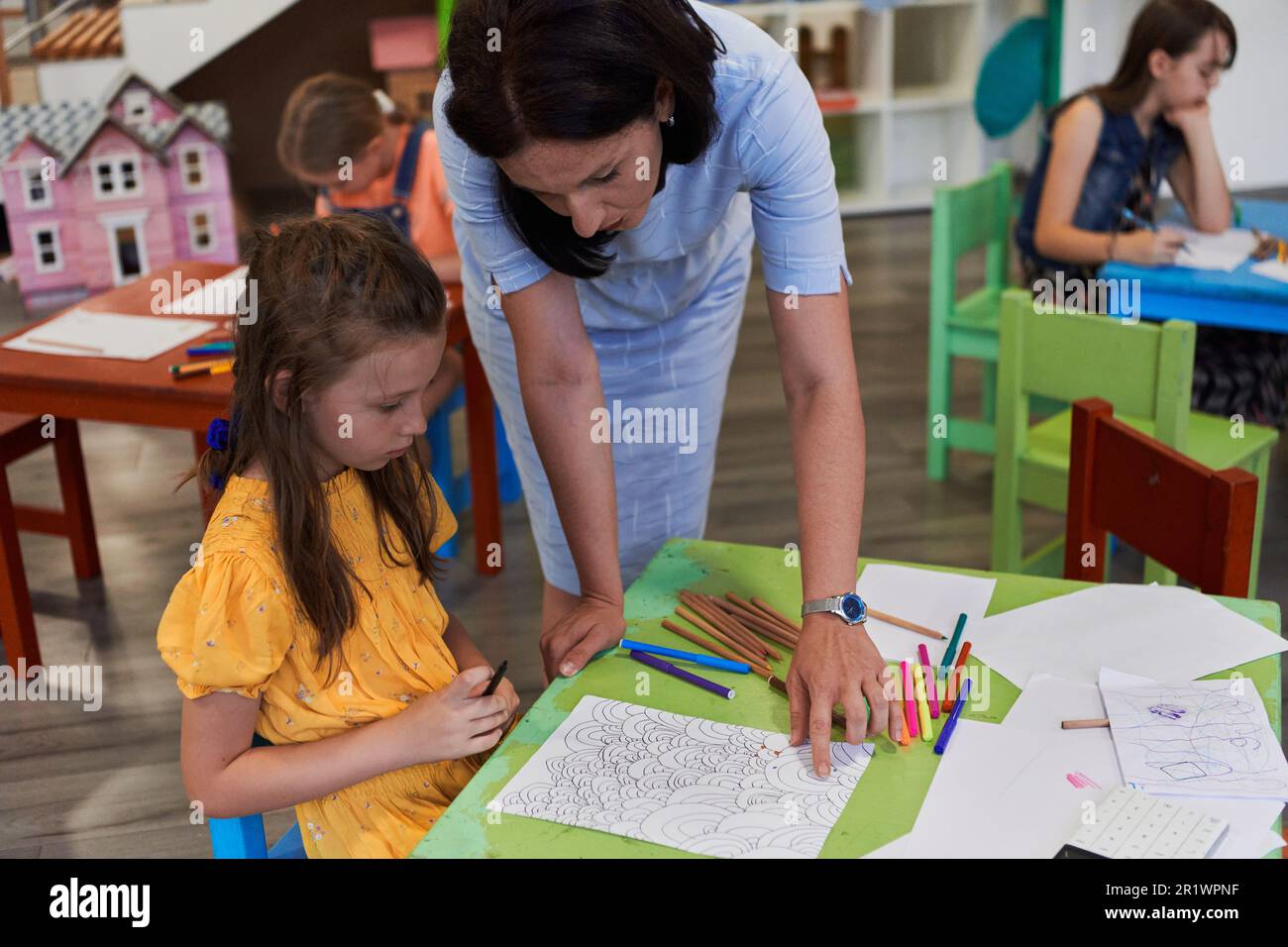 Creative kids during an art class in a daycare center or elementary school classroom drawing ...