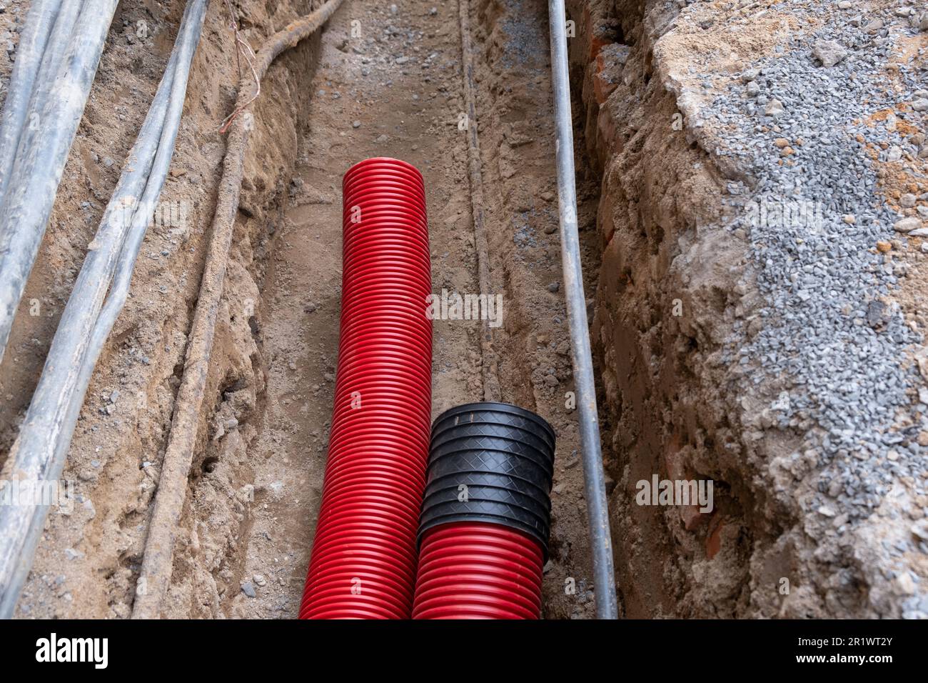 Red corrugated pipe are buried underground on the street made for ...