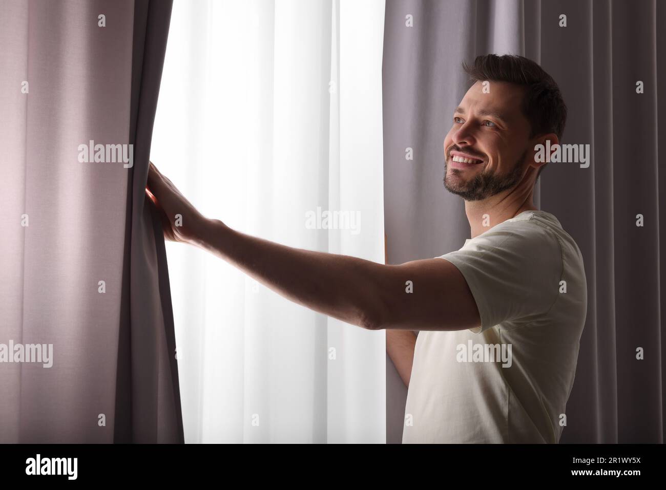 Man opening curtains hi-res stock photography and images - Alamy