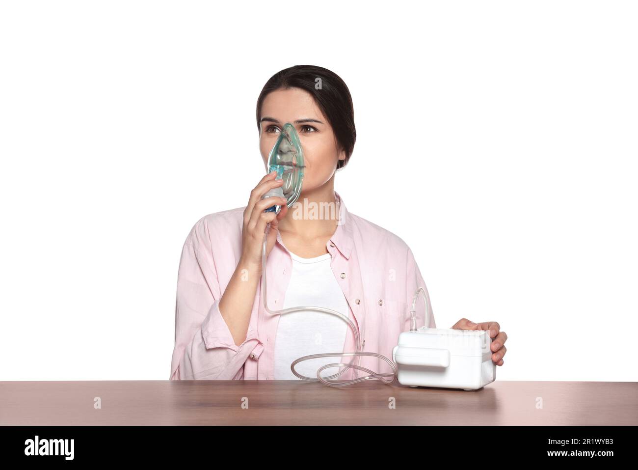 Young woman using nebulizer at wooden table on white background Stock ...