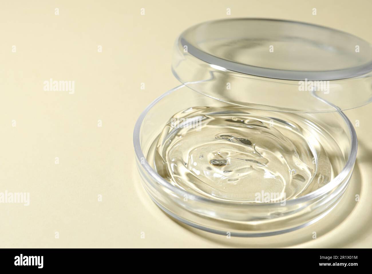 Petri dish with liquid and lid on beige background, closeup. Space for ...