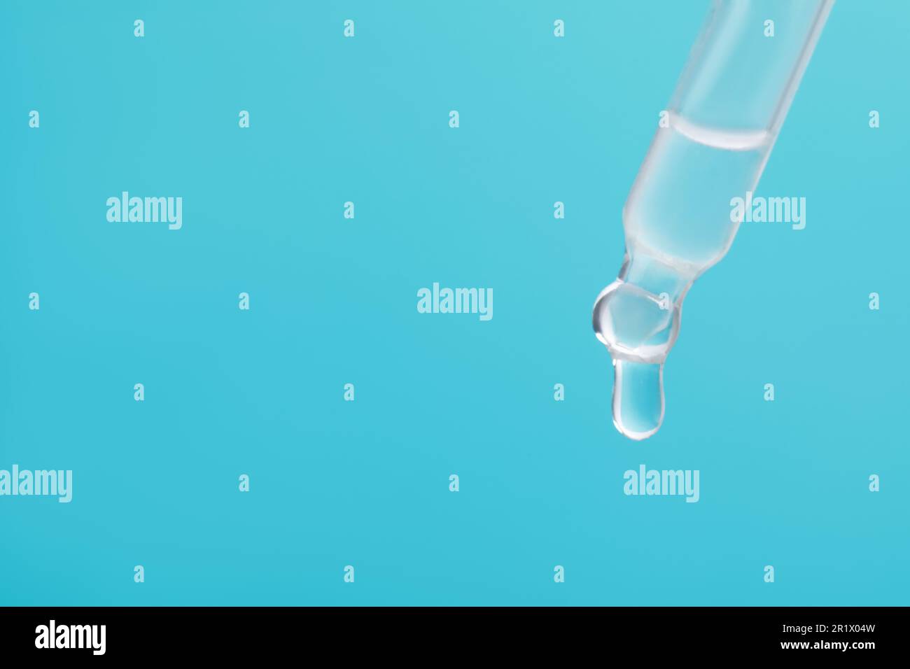 Dripping serum from pipette on light blue background, closeup. Space ...