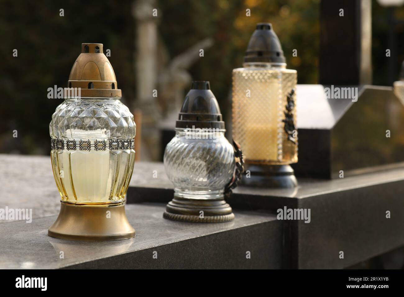 Different grave lanterns on granite tombstone outdoors, space for text. Funeral ceremony Stock ...