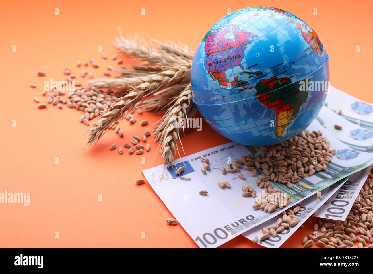 Import and export concept. Globe, ears of wheat and banknotes on orange ...