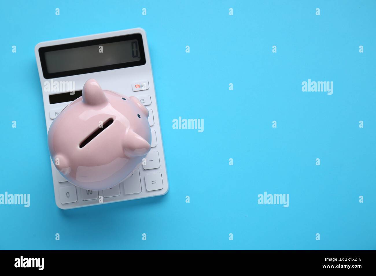 Piggy bank and calculator on light blue background, top view. Space for ...