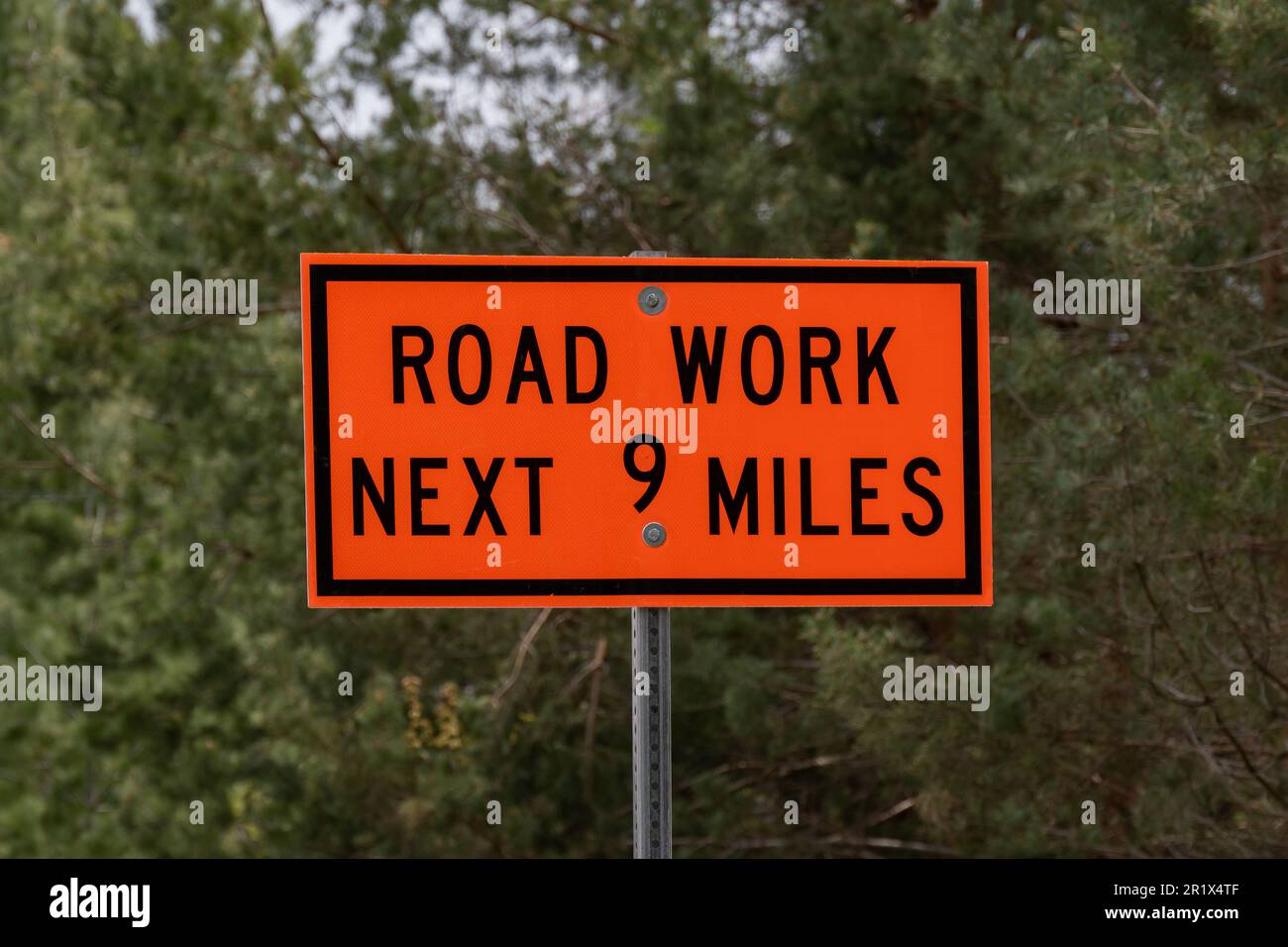 An orange road work next 9 miles sign Stock Photo - Alamy
