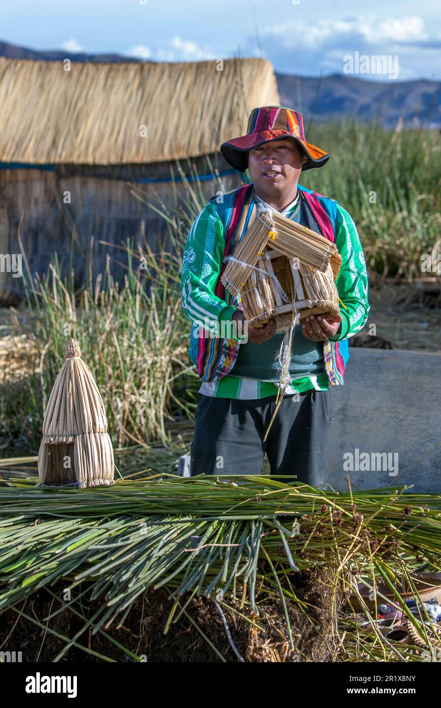 A man displays miniature reed houses modeled on the full size versions ...