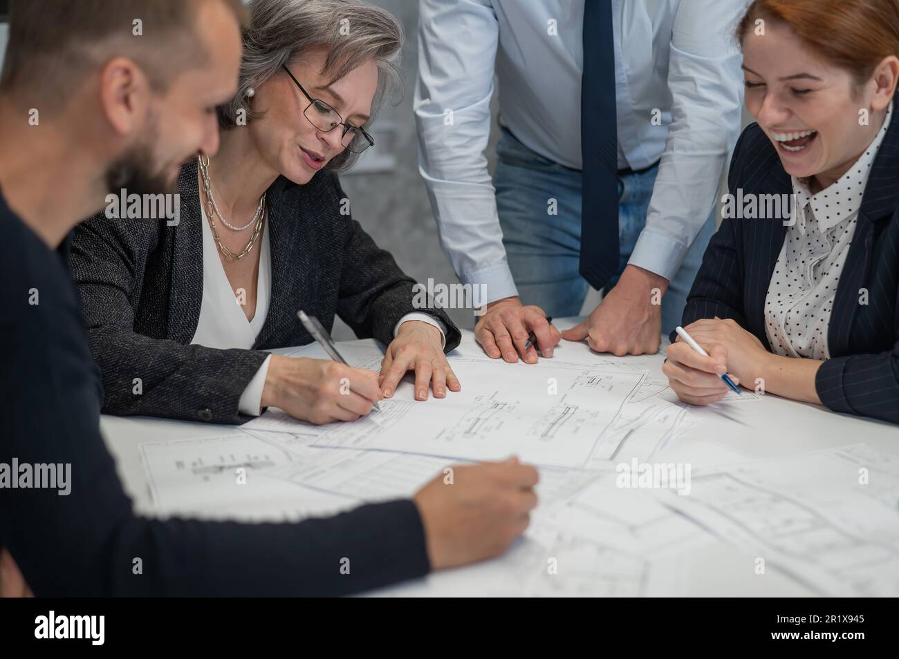Brainstorming of four engineers and architects with blueprints in the ...