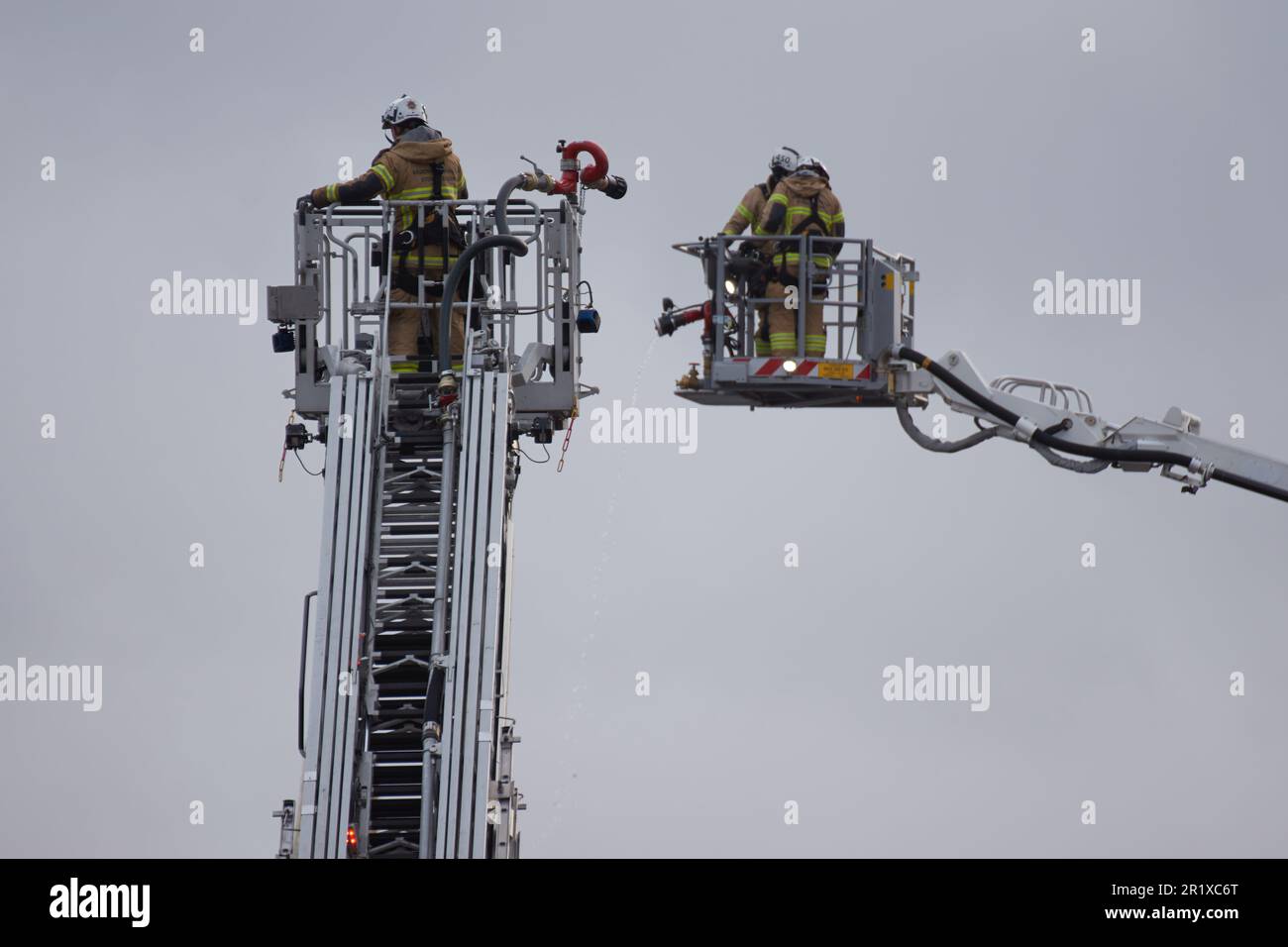 Two aerial ladders with fire fighters high up in the air Stock Photo ...