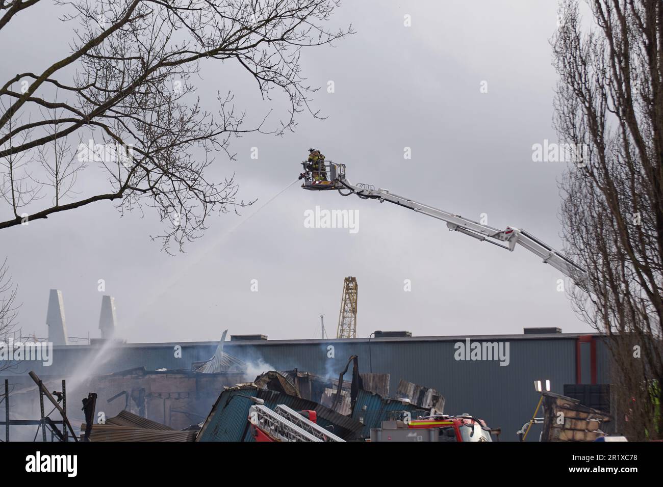 Two fire fighters on a aerial ladder high up in the air spraying water ...