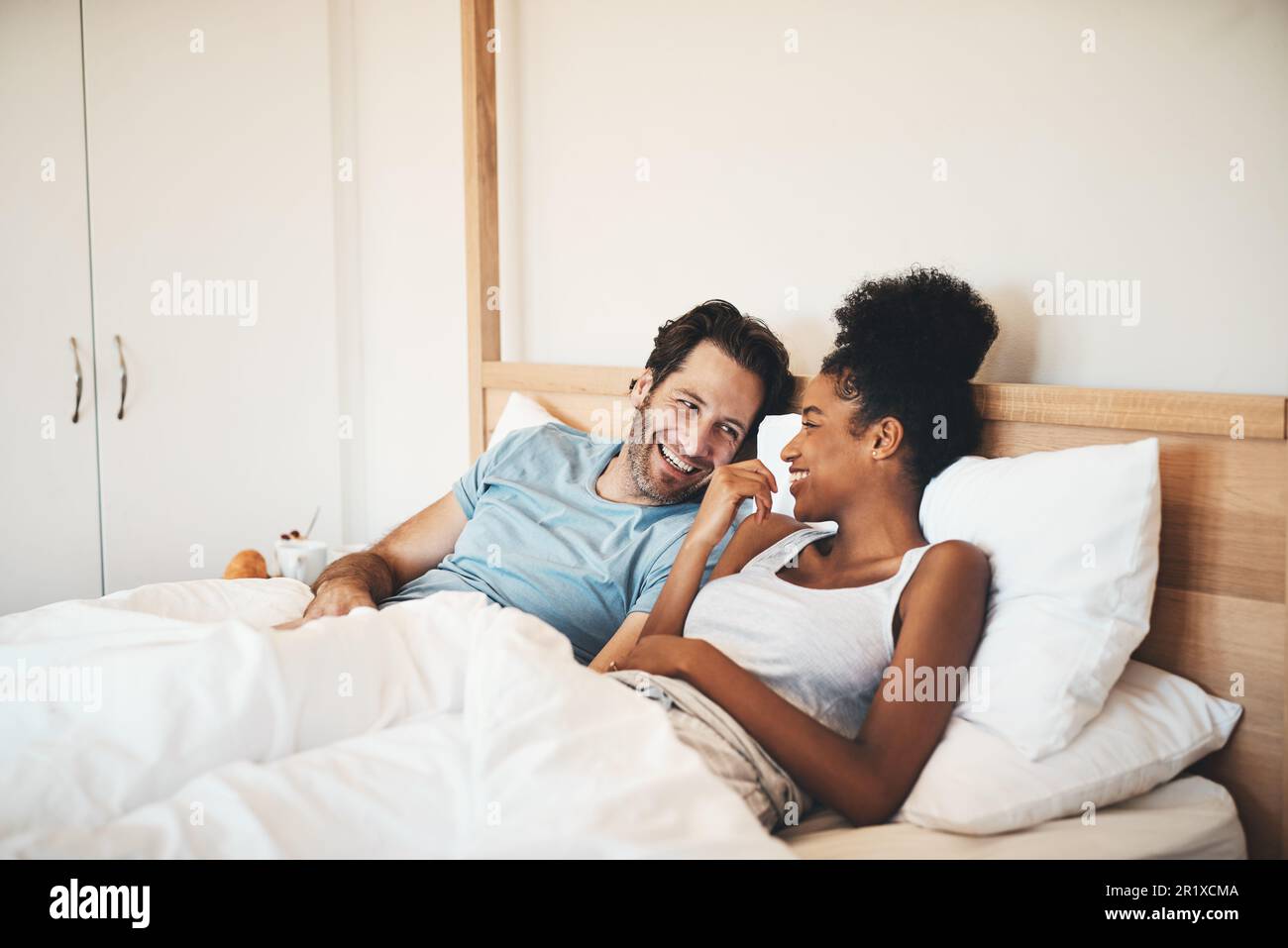 Interracial Couple Laughing And Relax On Bed For Morning Bonding