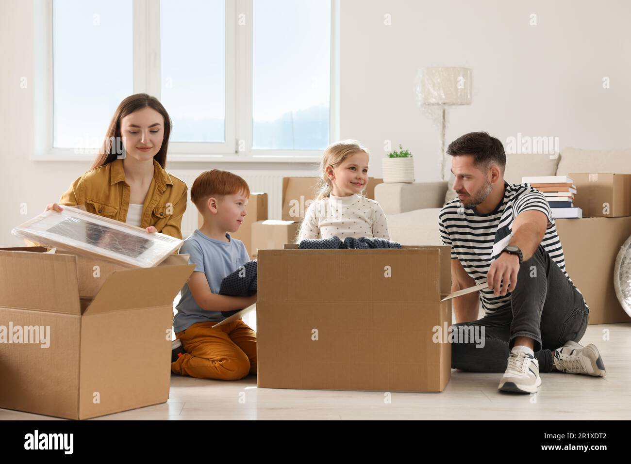 Happy family unpacking boxes in new apartment. Moving day Stock Photo ...