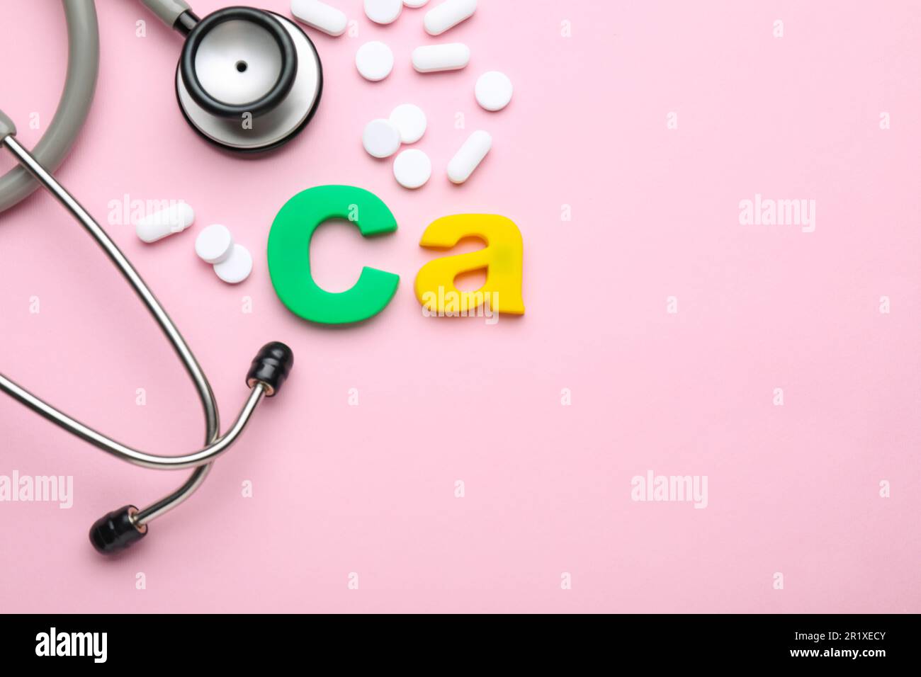Stethoscope, pills and calcium symbol made of colorful letters on pink ...