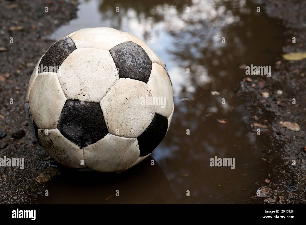 Dirty soccer ball in muddy puddle, space for text Stock Photo - Alamy