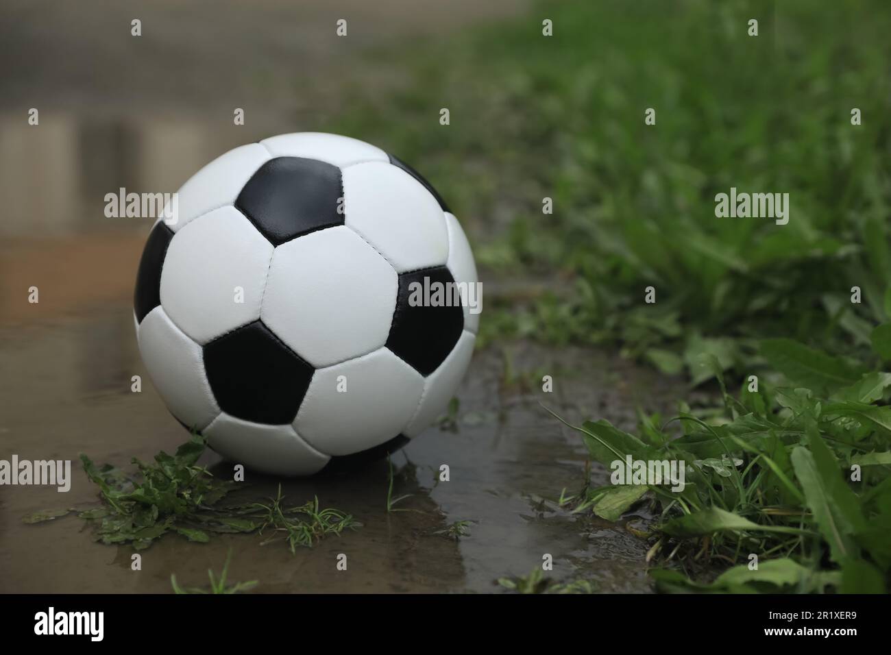 Soccer ball in puddle outdoors, space for text Stock Photo - Alamy