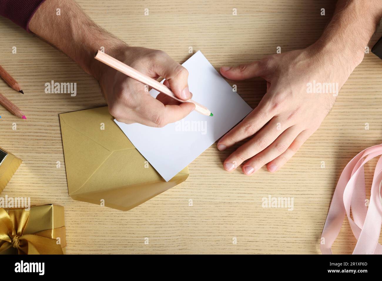 Man writing message in greeting card at wooden table, top view Stock ...