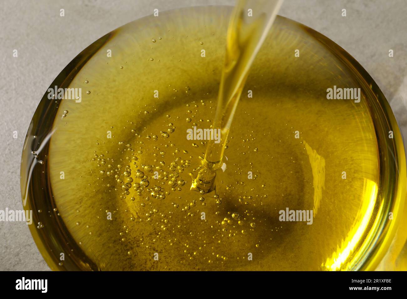 Pouring cooking oil into glass bowl, closeup Stock Photo - Alamy