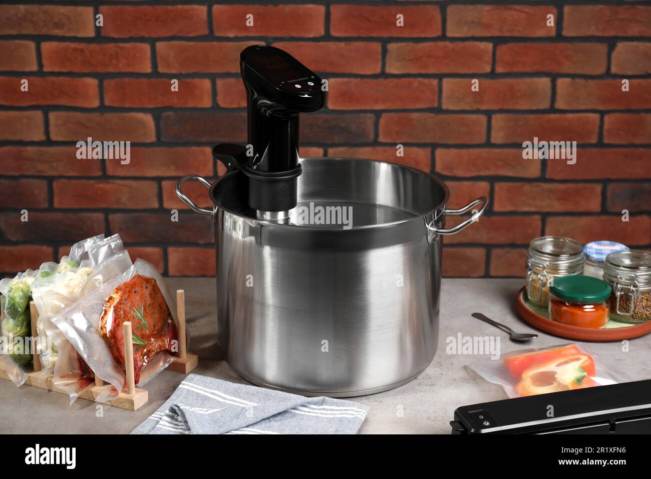 Thermal immersion circulator in pot and ingredients on beige table ...