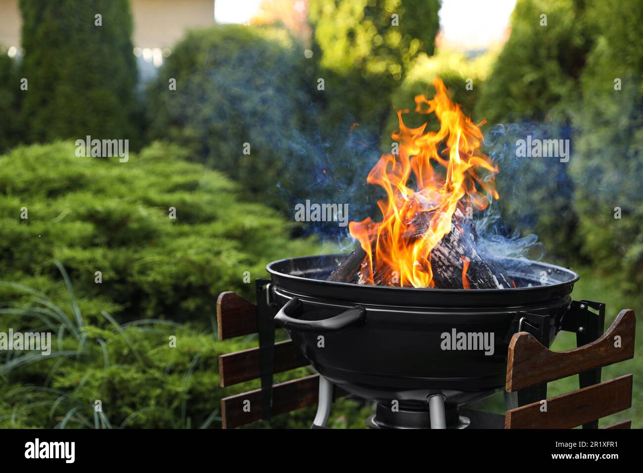 Portable barbecue grill with fire flames outdoors. Space for text Stock ...
