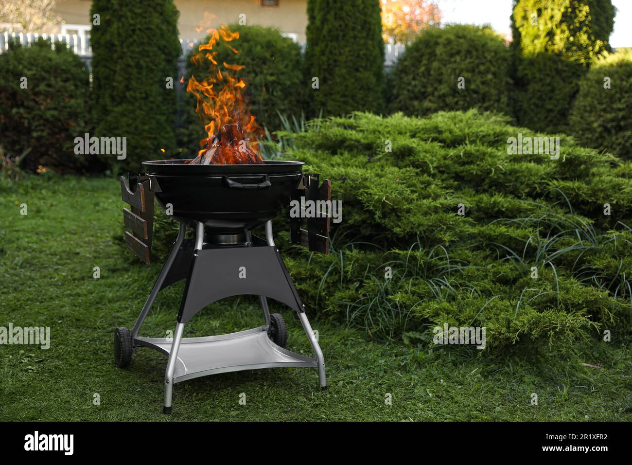 Portable barbecue grill with fire flames outdoors. Space for text Stock ...