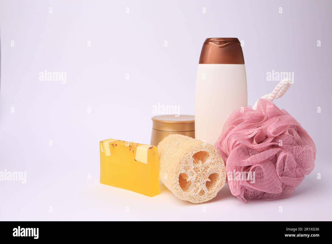 Pink shower puff, loofah sponge and cosmetic products on white ...