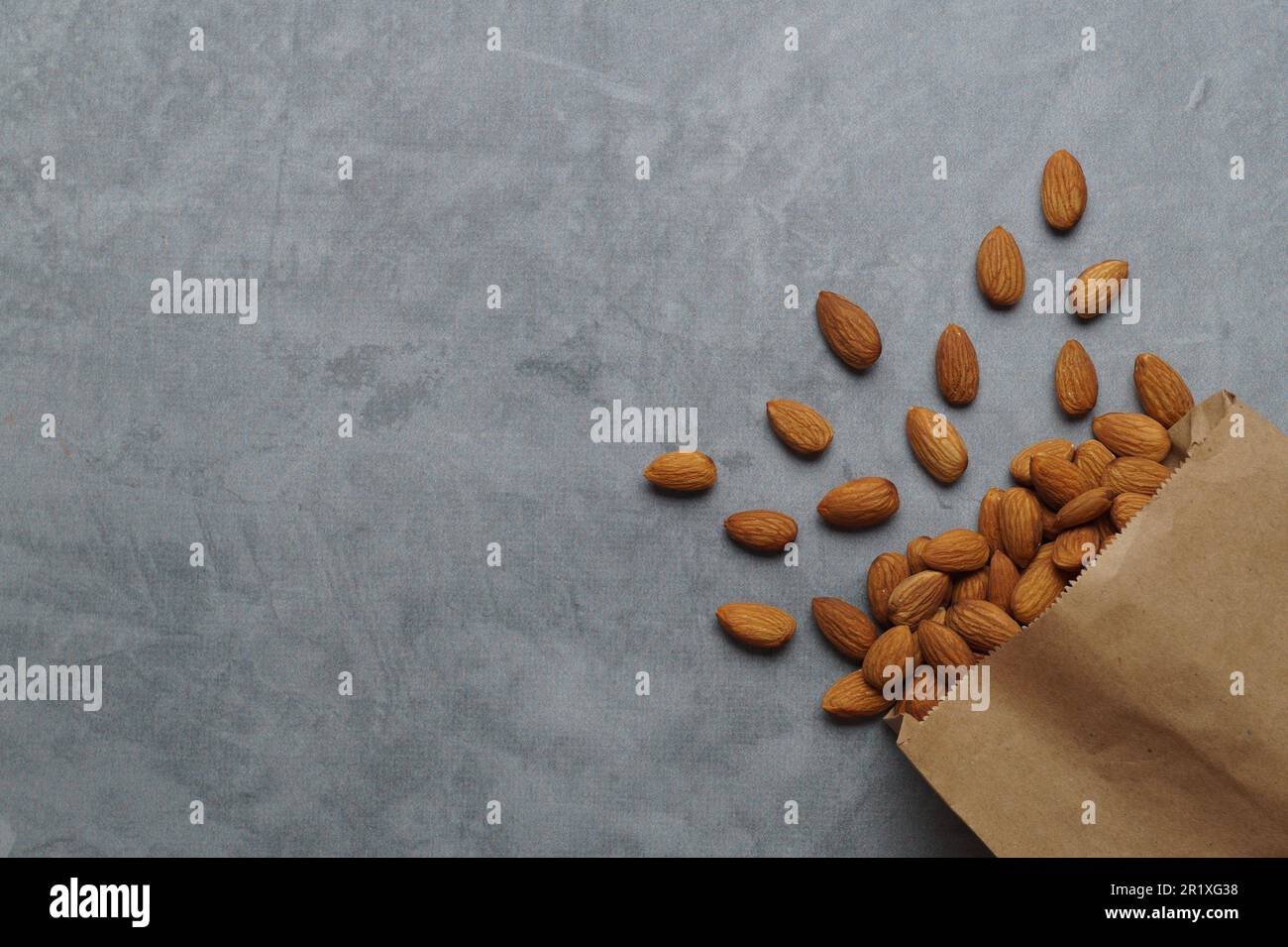 Paper bag with delicious almonds on grey table, top view. Space for ...