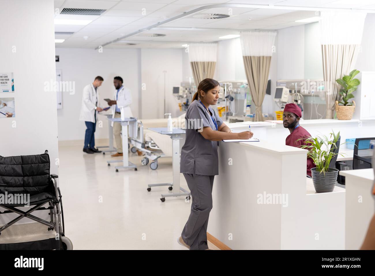 Asian female doctor writing on clipboard at reception desk of hospital ...