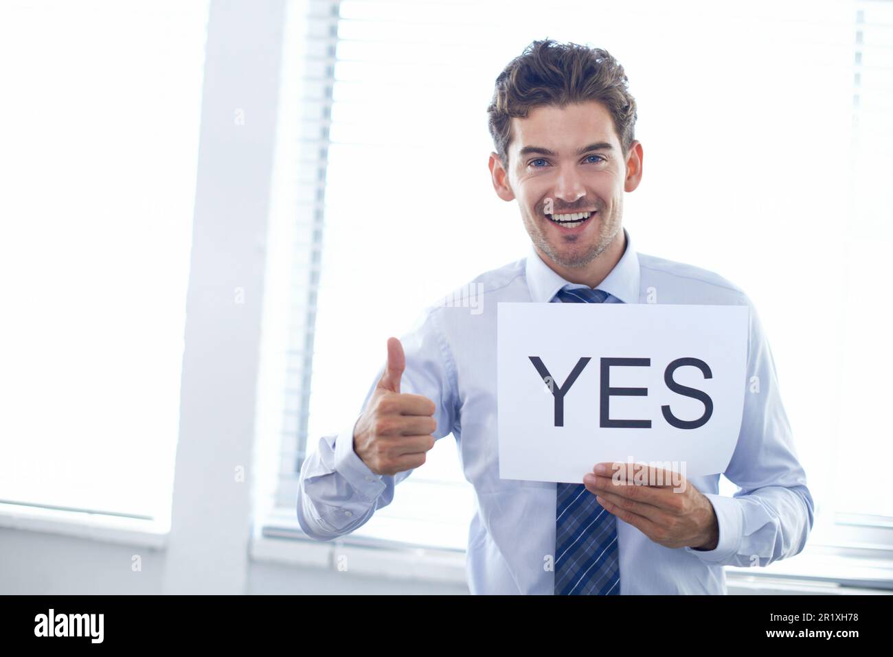 YES. a handsome young businessman holding a yes sign and giving the ...