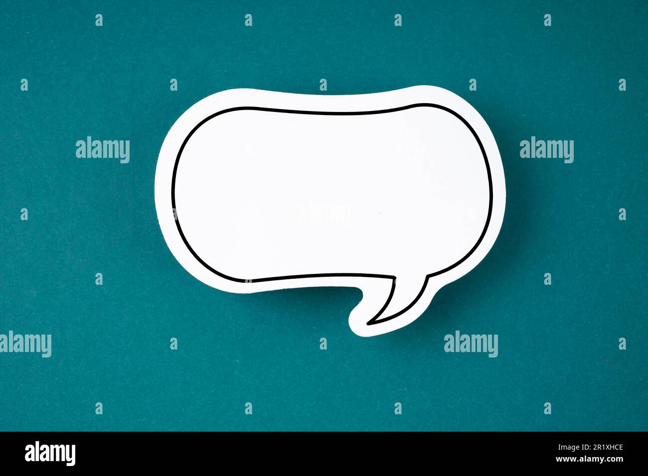 White speech bubble shaped post it note on green background with copy ...