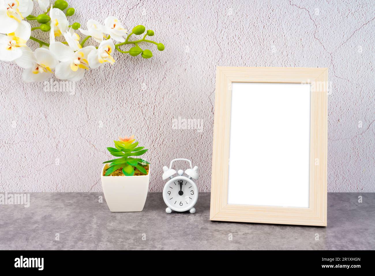 Blank picture frame and alarm clock on black floor with copy space and ...