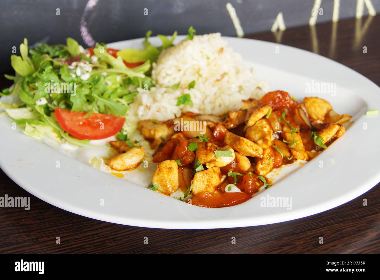 Braised chicken with vegetables and some rice and salad Stock Photo - Alamy