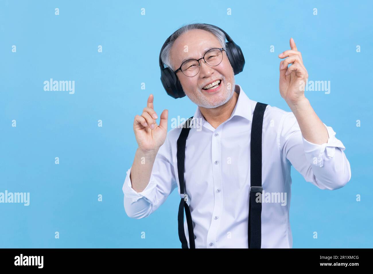 active young senior Korean Asian male listenint to music with headset ...