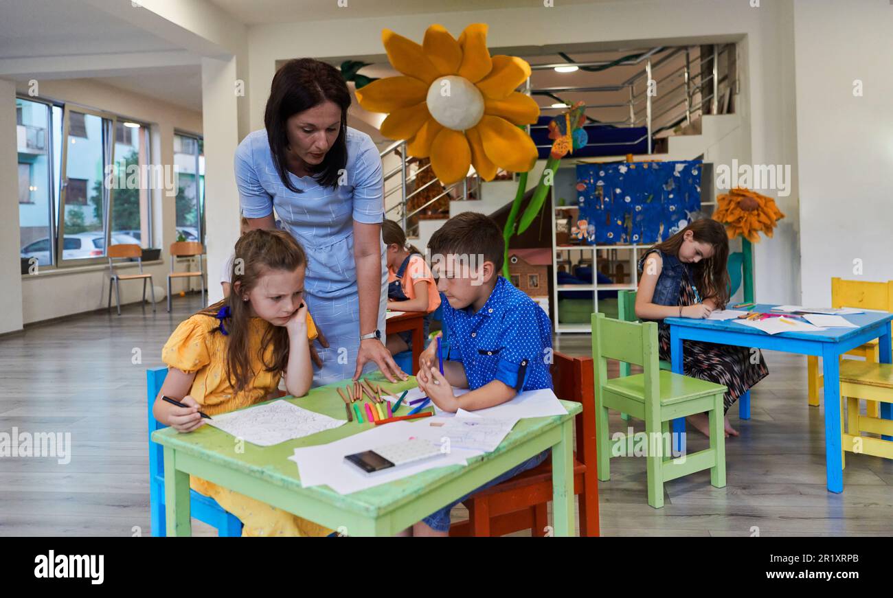 Creative kids during an art class in a daycare center or elementary school classroom drawing ...