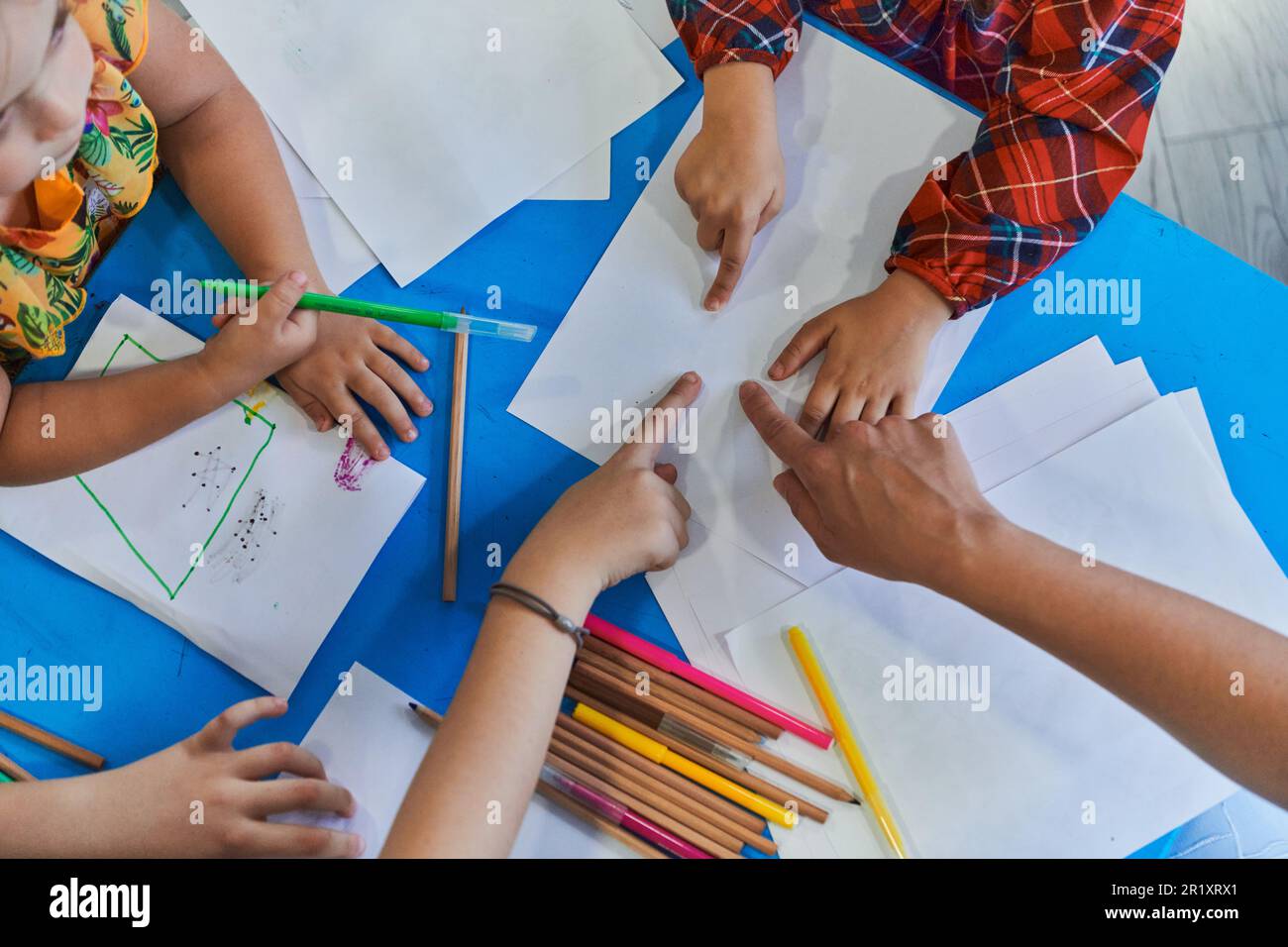 Creative kids during an art class in a daycare center or elementary school classroom drawing ...