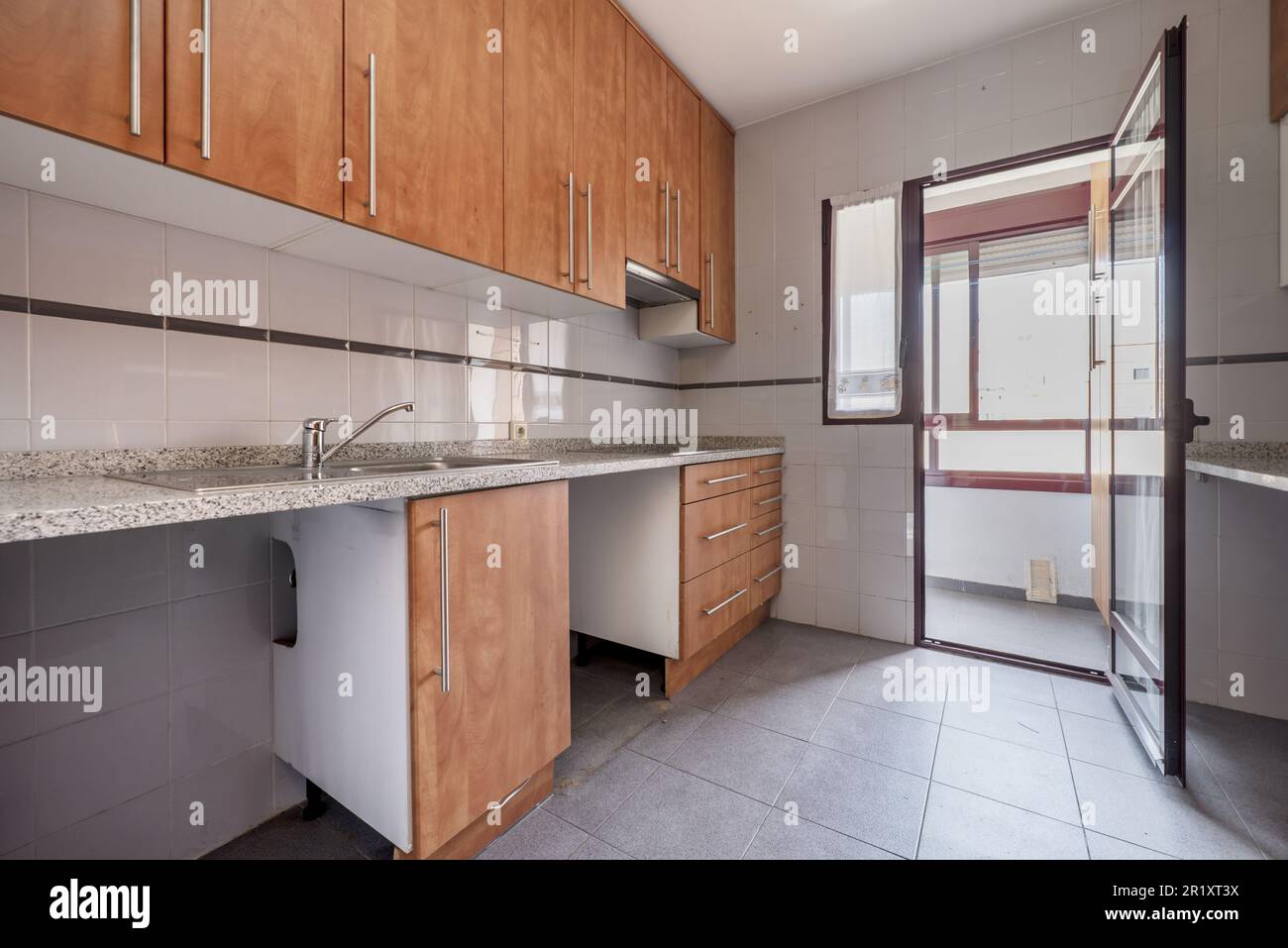 A small kitchen furnished with wooden furniture, a gray granite ...