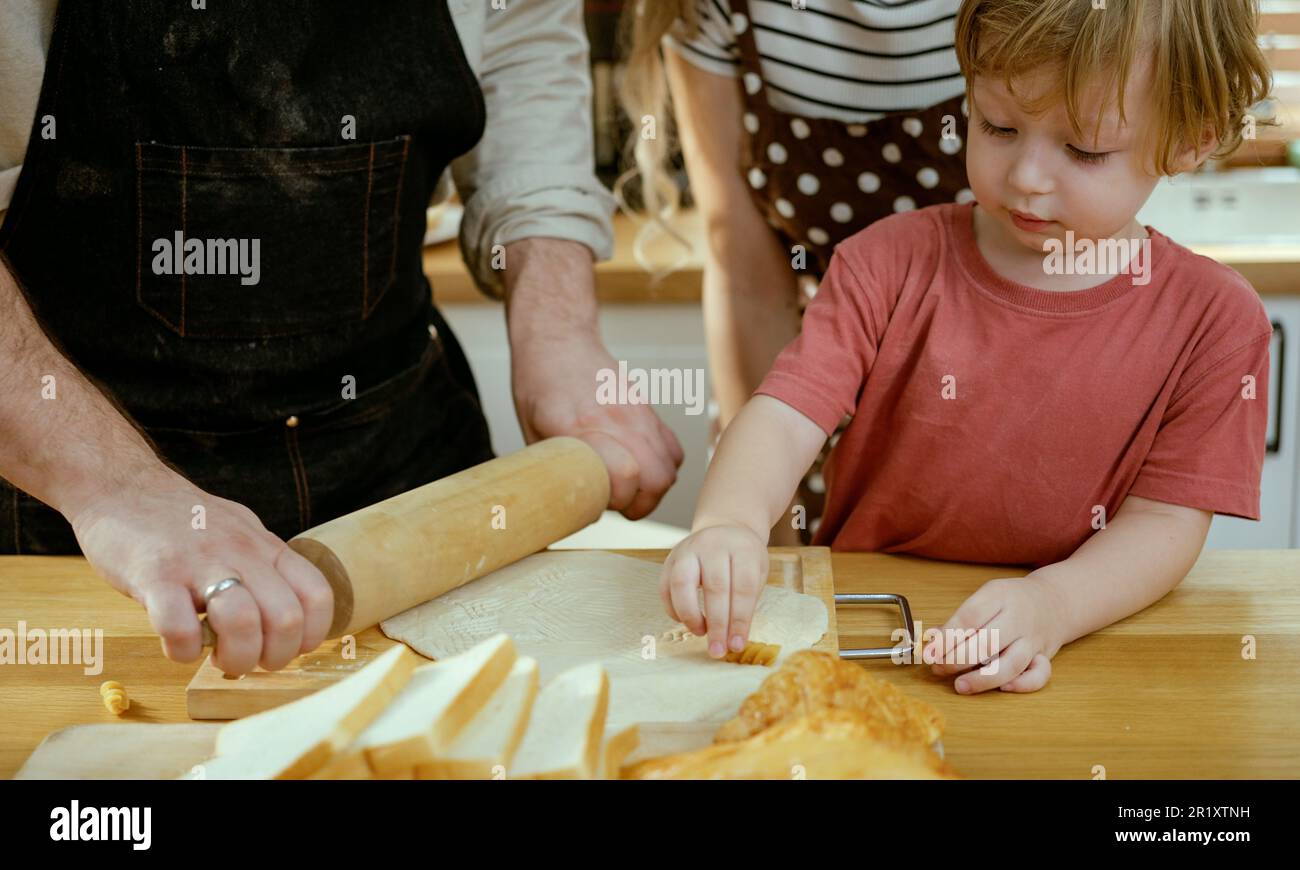 Happy young family enjoying making pie dough or pastries in modern ...