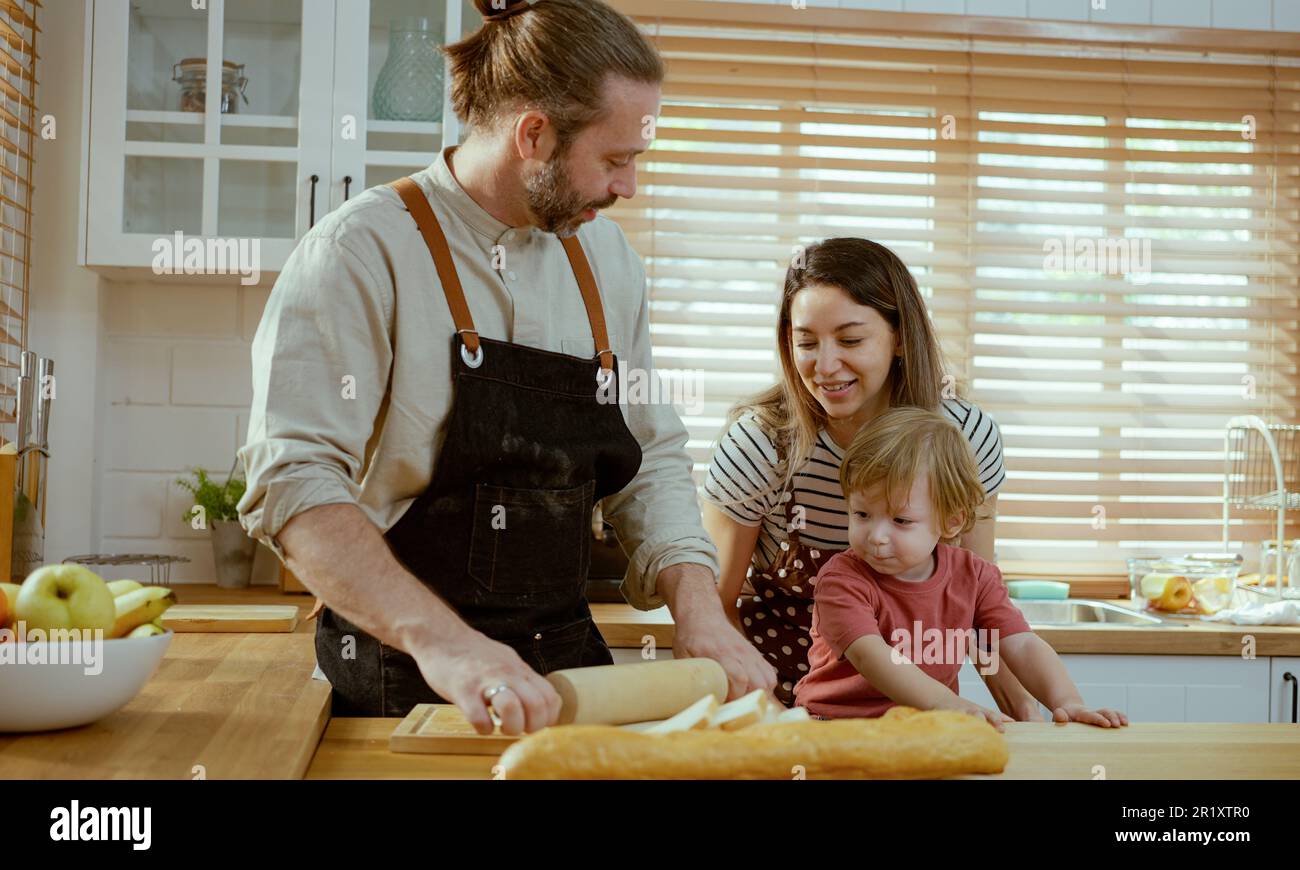 Happy young family enjoying making pie dough or pastries in modern ...
