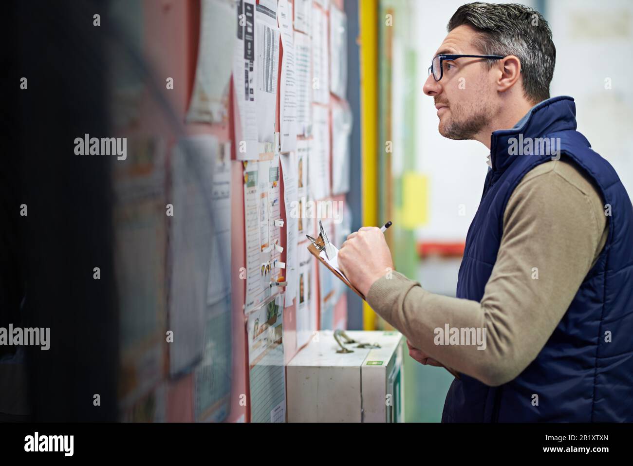 Updating the notice board for his staff. a manager writing on a ...