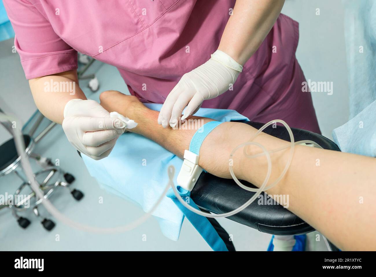 The doctor in sterile gloves wipes the patient's hand with an alcohol ...