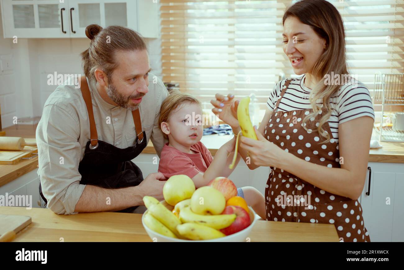 Happy family eating fruits in the kitchen Stock Photo - Alamy