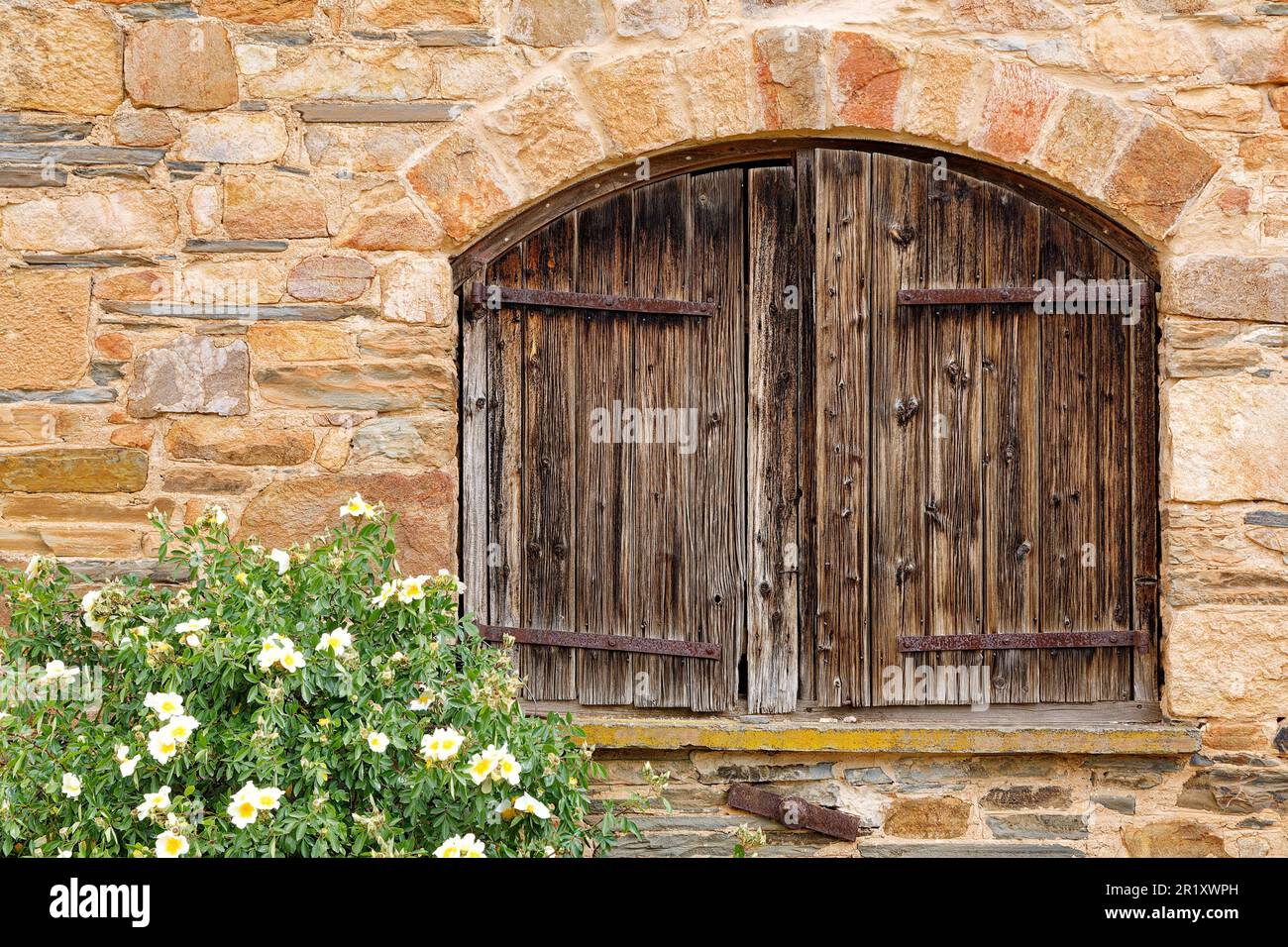 A traditional wooden window of an old stone building with flowers ...